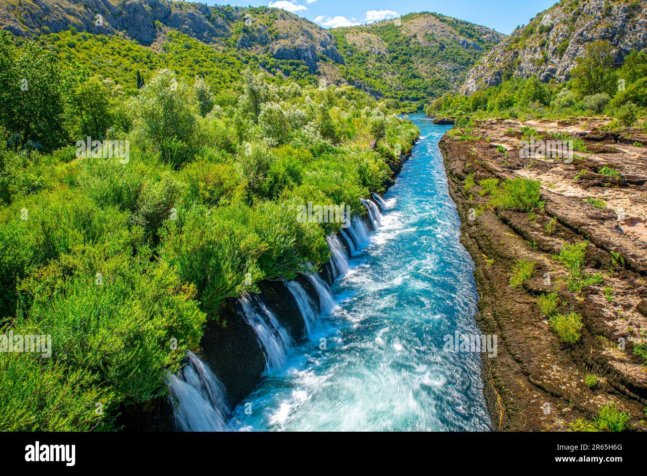 Aerial view of a lush green ravine with a winding river snaking through ...