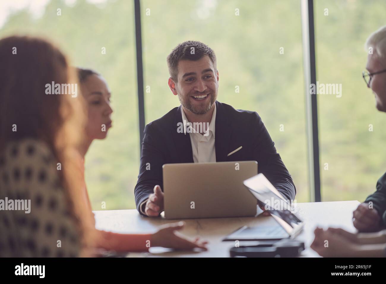 A diverse group of business professionals gathered at a modern office ...
