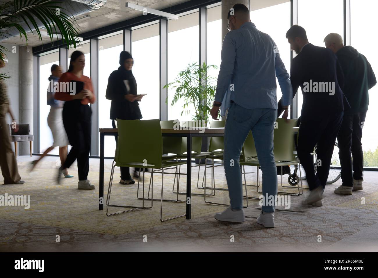 A diverse group of business professionals gathers around a table for meetings, engaging in ...