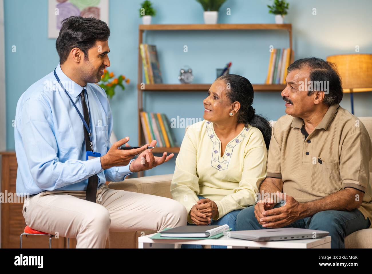 Professional Indian banker explaining about insurance policy to senior ...
