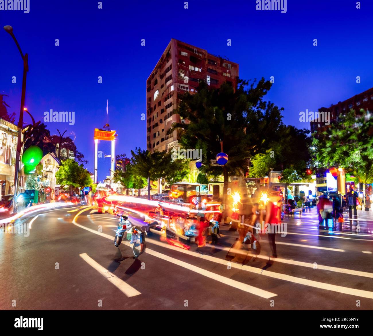 A vibrant night scene of busy city streets illuminated by street lights ...