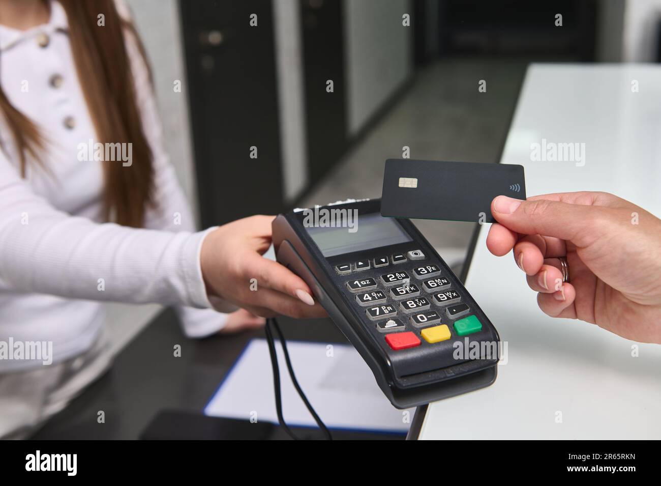 Close up manager at reception counter holding out POS terminal to ...