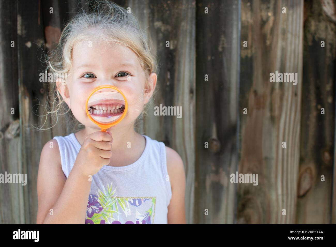Smiling Caucasian preschool girl with magnifying glass. Happy childhood ...