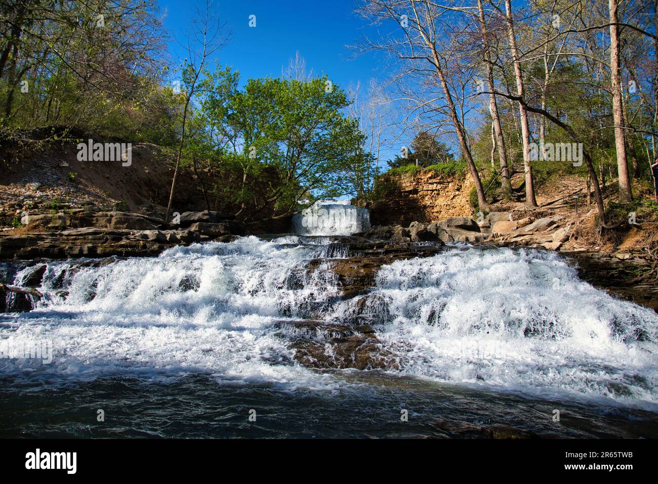 An expansive and majestic waterfall cascades over a rugged terrain of ...