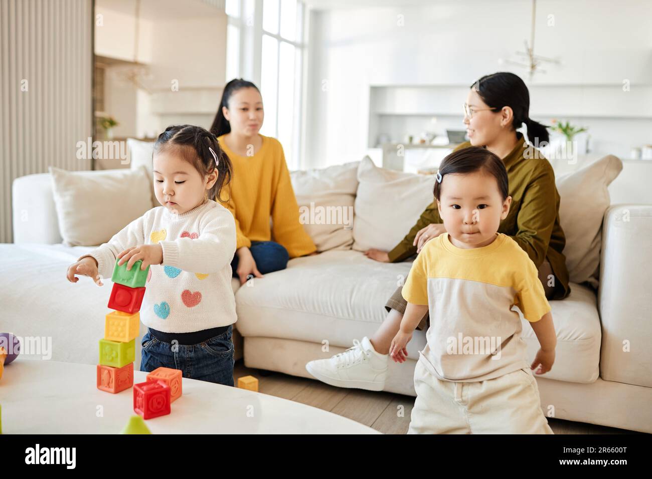 Children playing toys together while their mothers talking to each ...