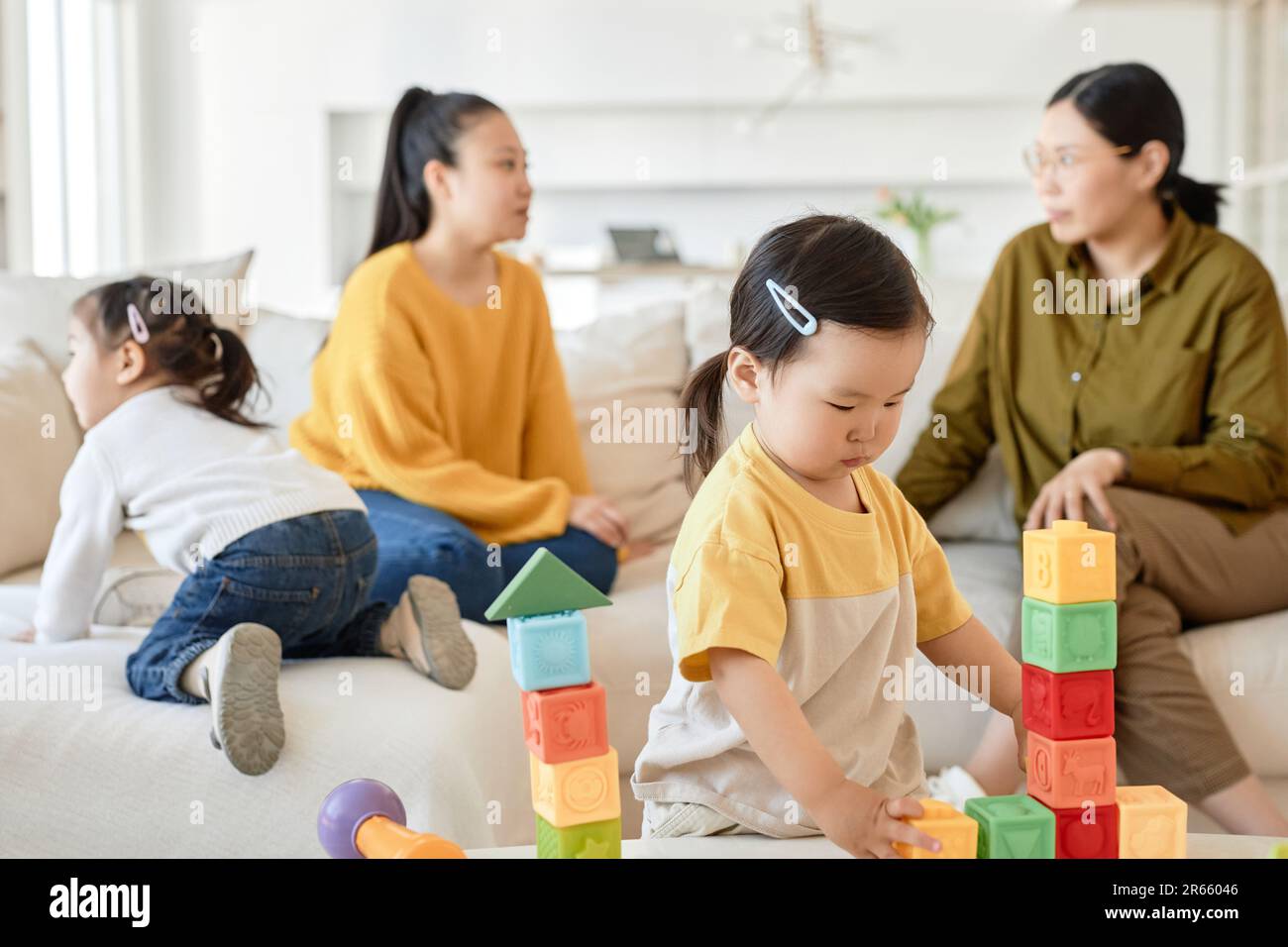 Children playing toys while their moms talking in background in the ...