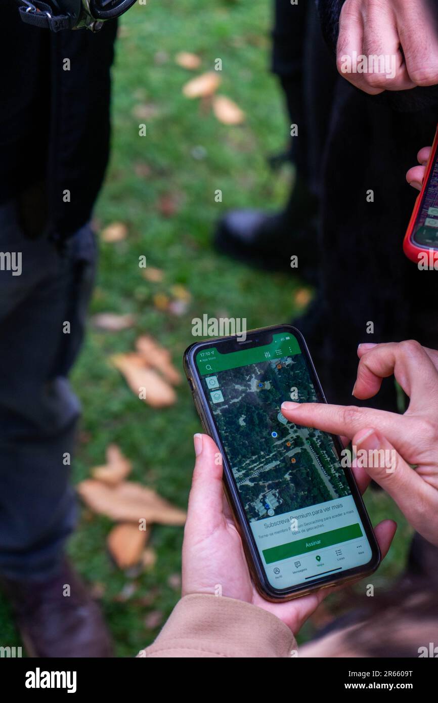 People's hands moving a map on their cell phones to play geocaching in ...