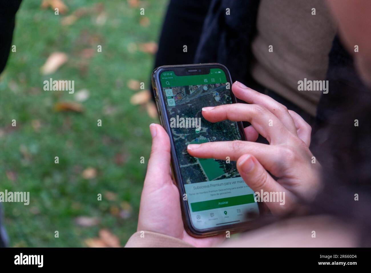 People's hands moving a map on their cell phones to play geocaching in ...