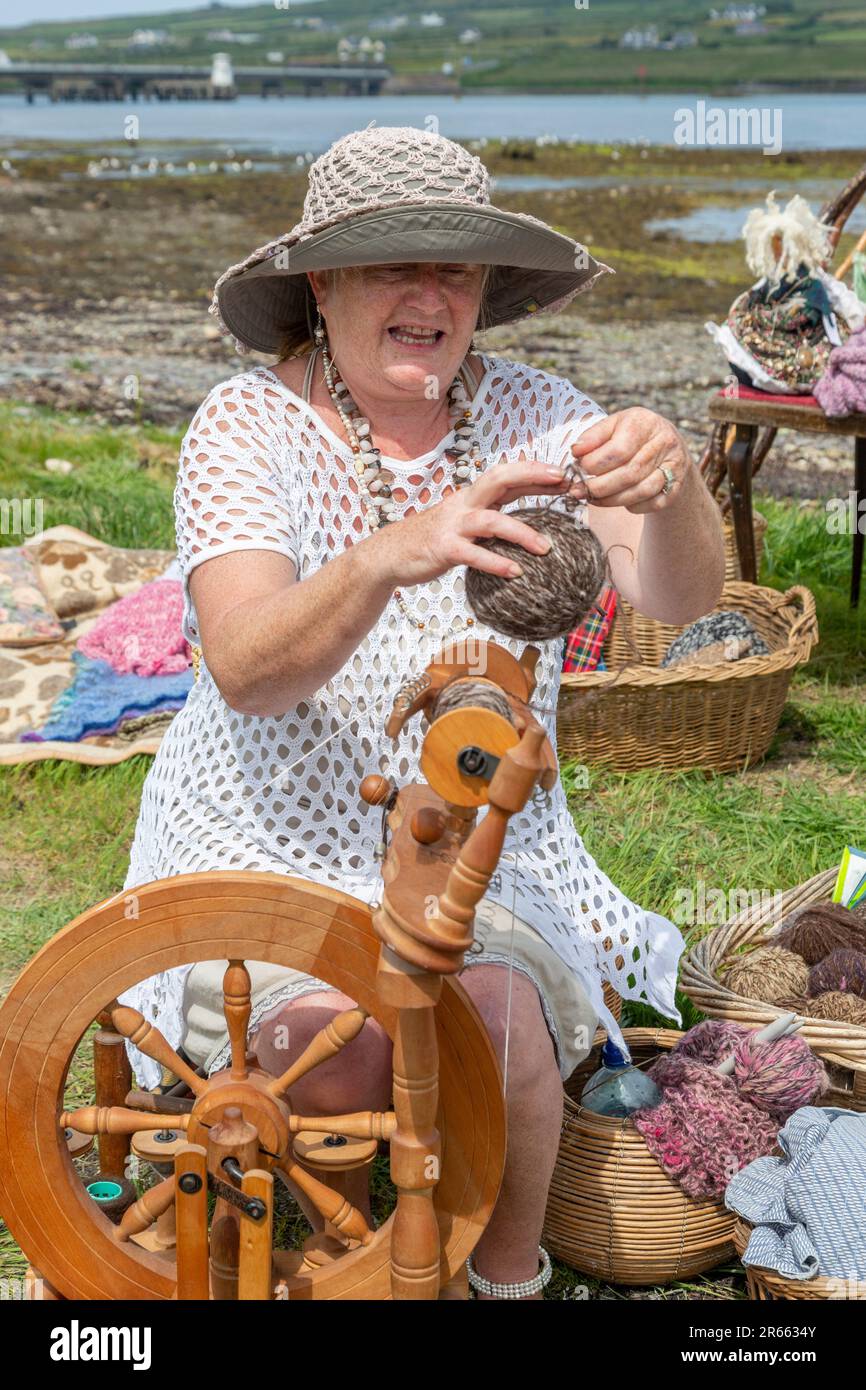 Senior Woman with spinning wheel, balls of wool and woven articles ...