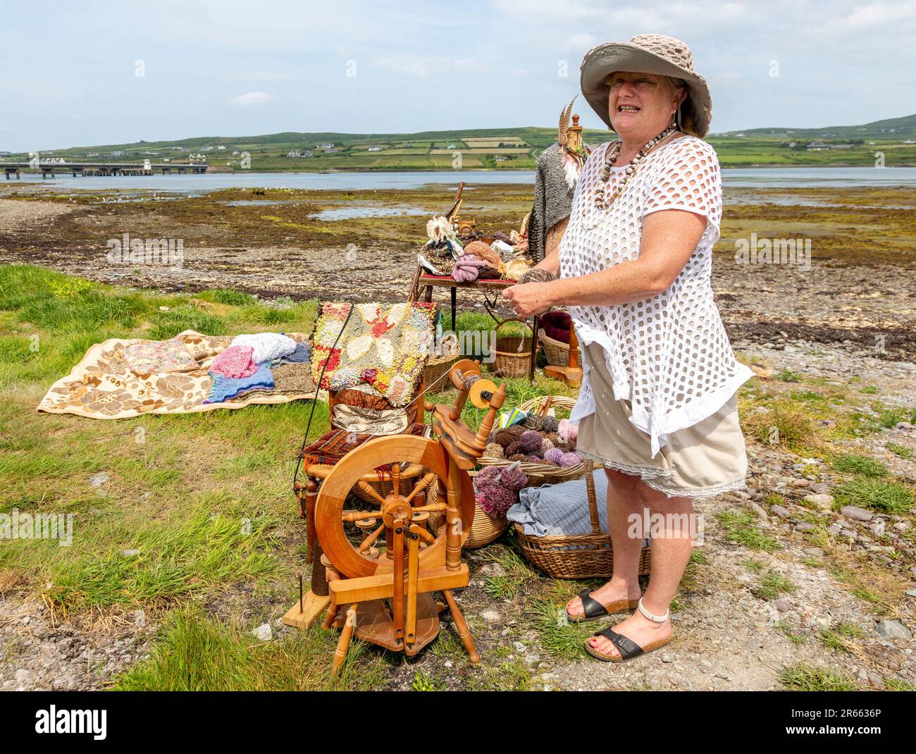 Senior Woman with spinning wheel, balls of wool and woven articles ...