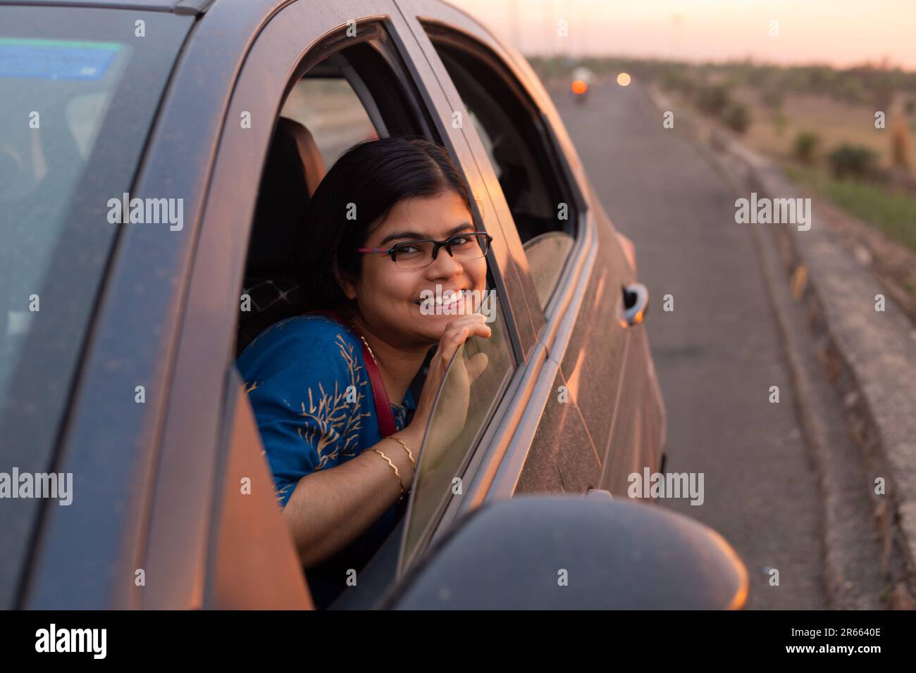 A beautiful young Indian woman looking out of car window with smiling ...