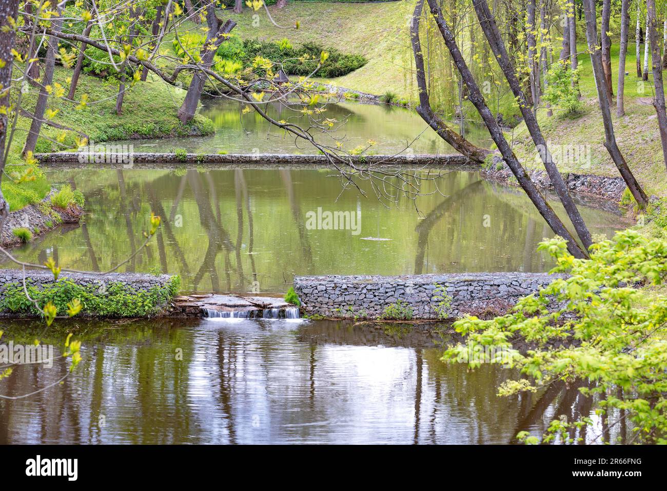 A cascading pond with stone watersheds and banks with a mini waterfall ...
