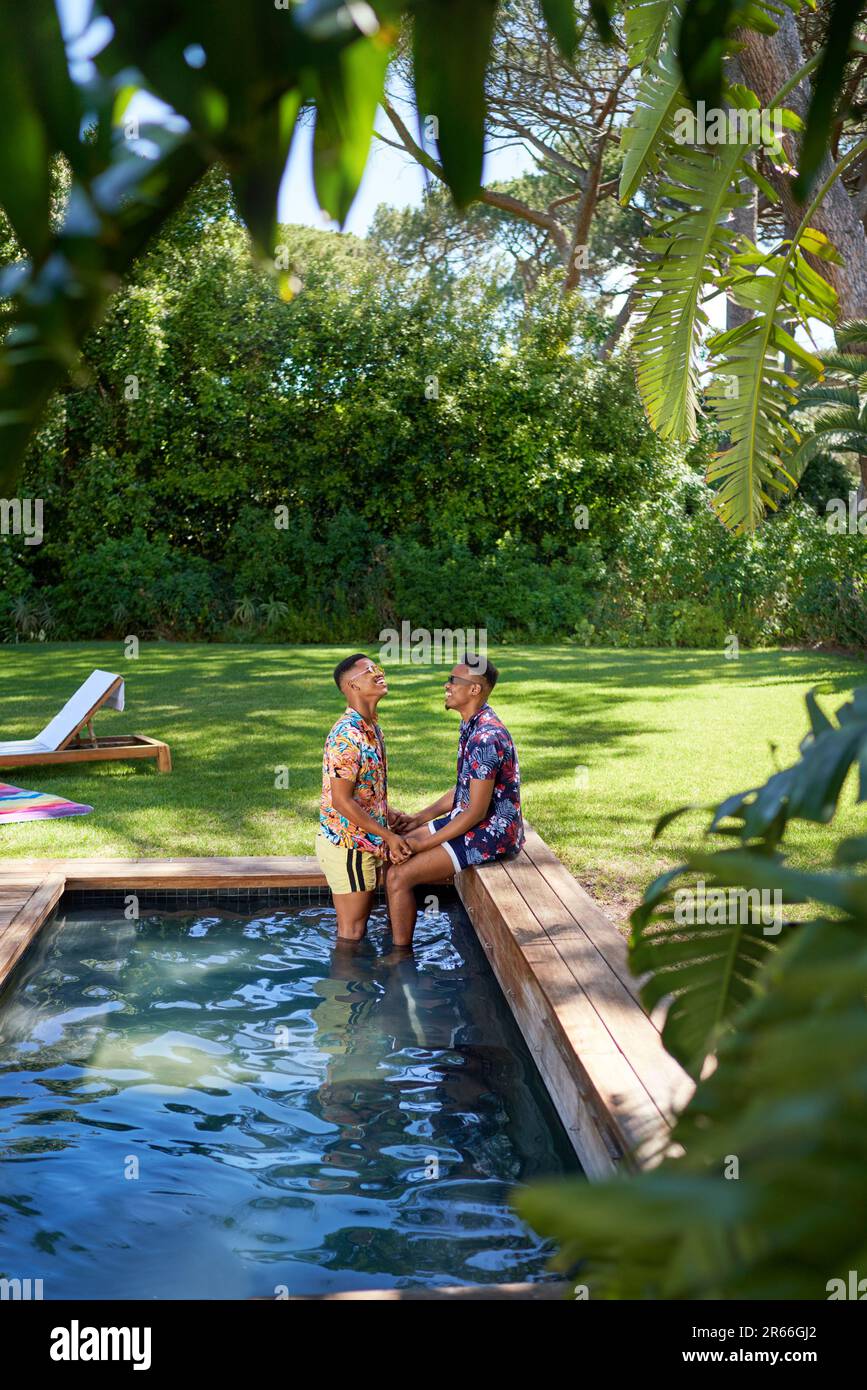 Young gay male couple relaxing at swimming pool in summer backyard Stock Photo - Alamy