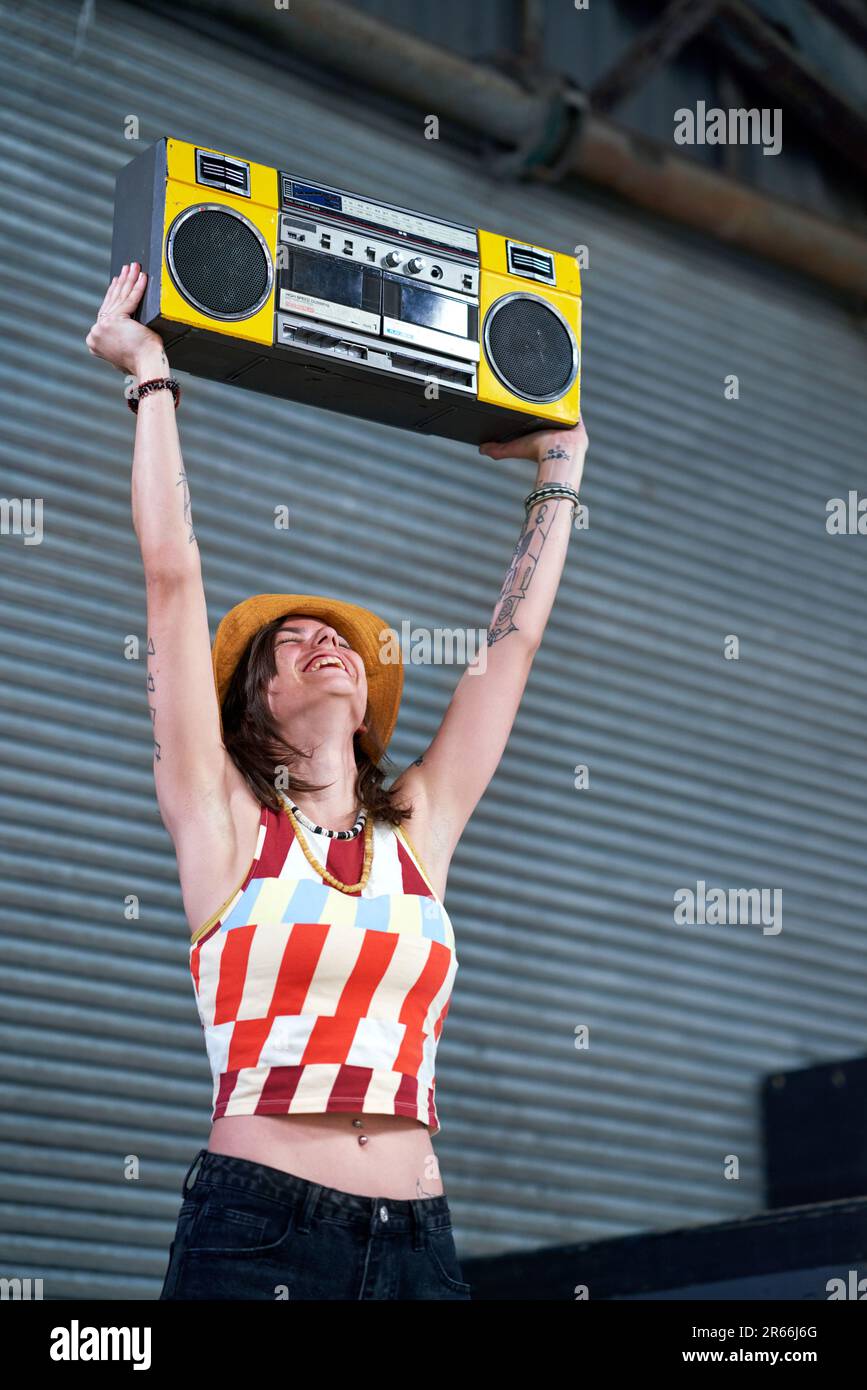 Carefree young woman holding boom box overhead in alley Stock Photo - Alamy
