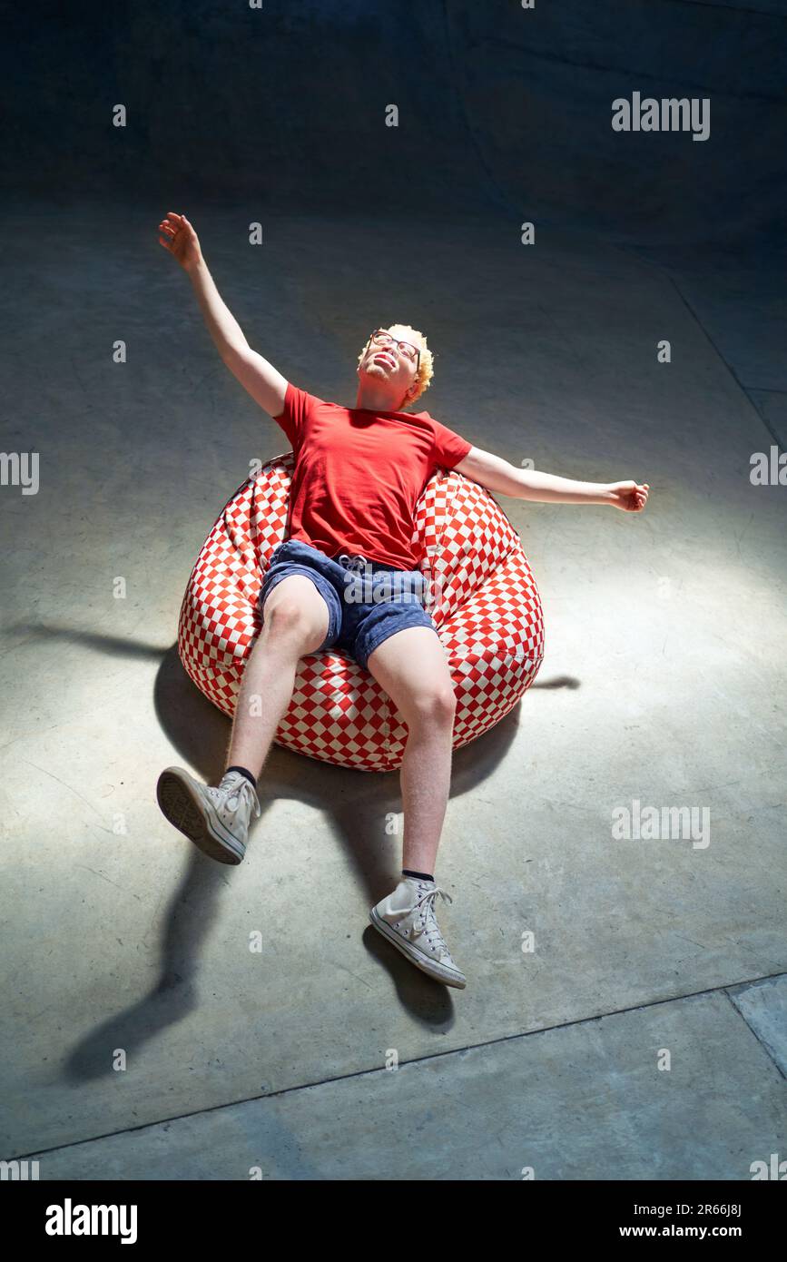Portrait carefree young man falling back on bean bag chair Stock Photo ...