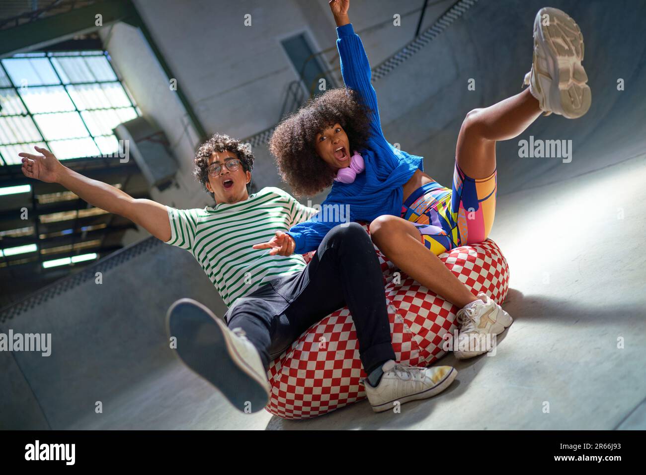 Portrait playful young friends falling, gesturing on bean bag chair ...