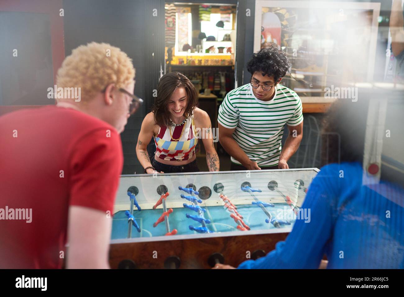 Happy young friends playing foosball in game room Stock Photo - Alamy
