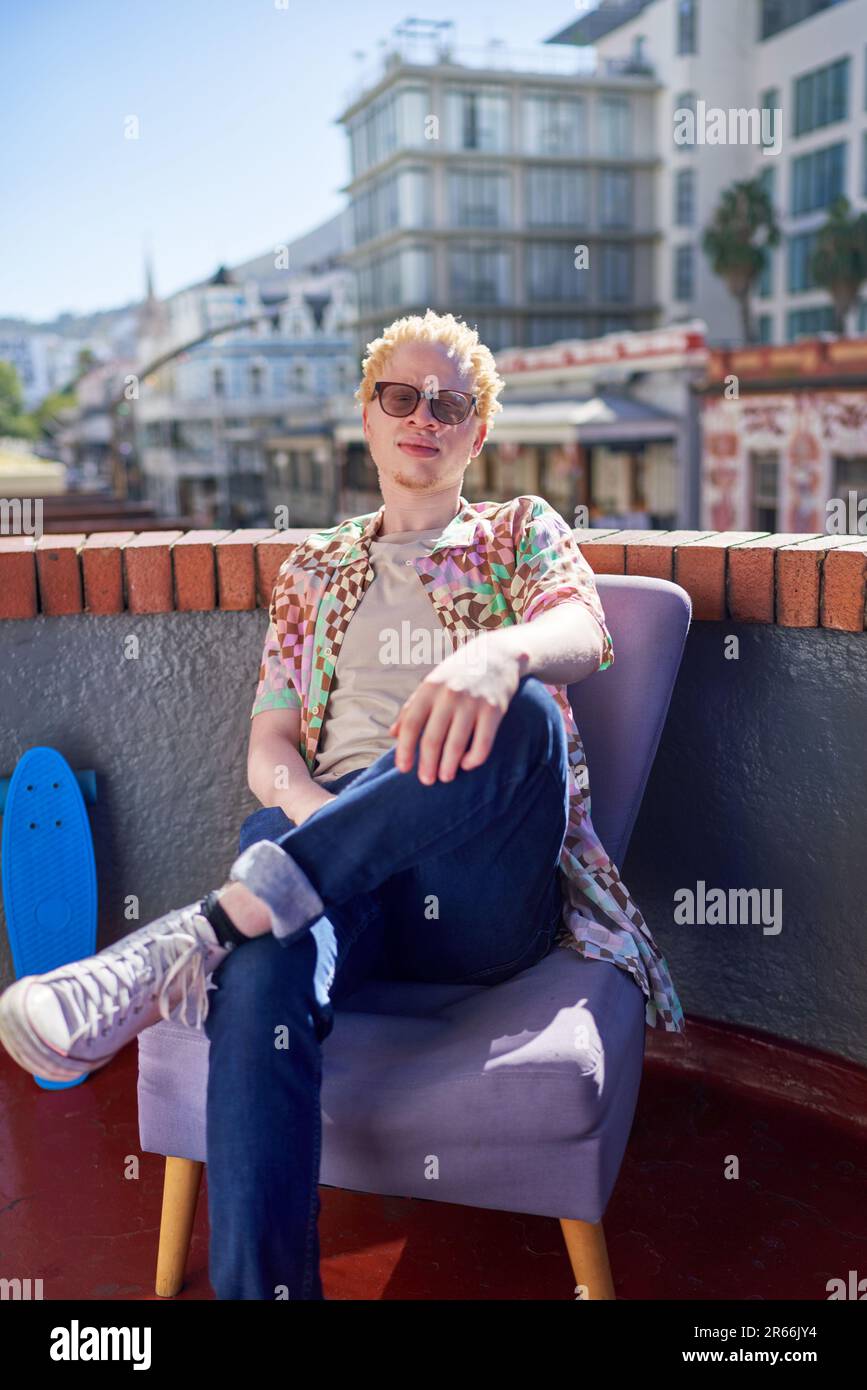 Portrait confident, cool young man sitting on sunny urban rooftop Stock ...