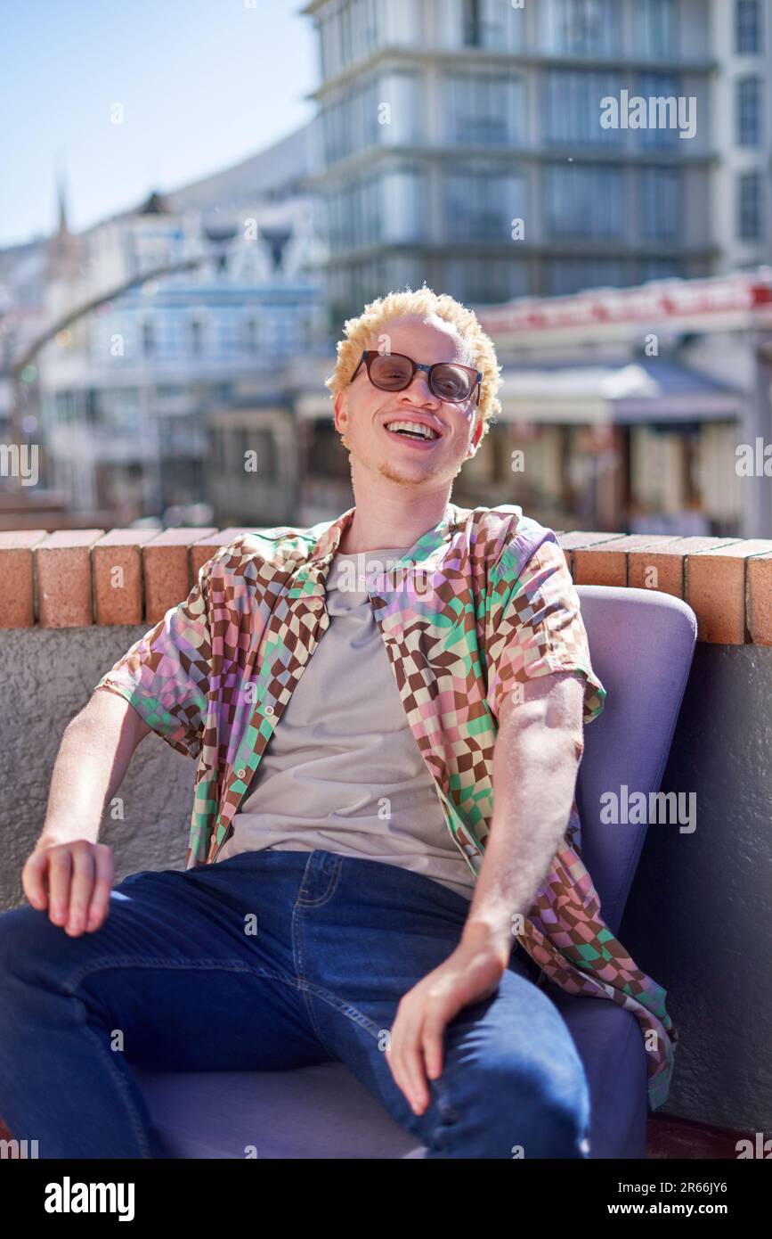 Portrait happy young albino man sitting on sunny city rooftop Stock ...