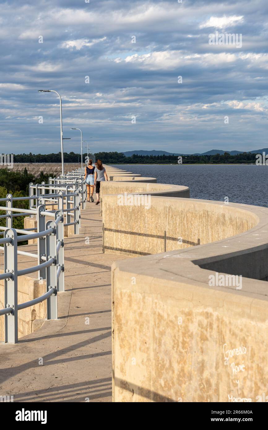 An attractive young couple walking along a beach promenade, enjoying a ...