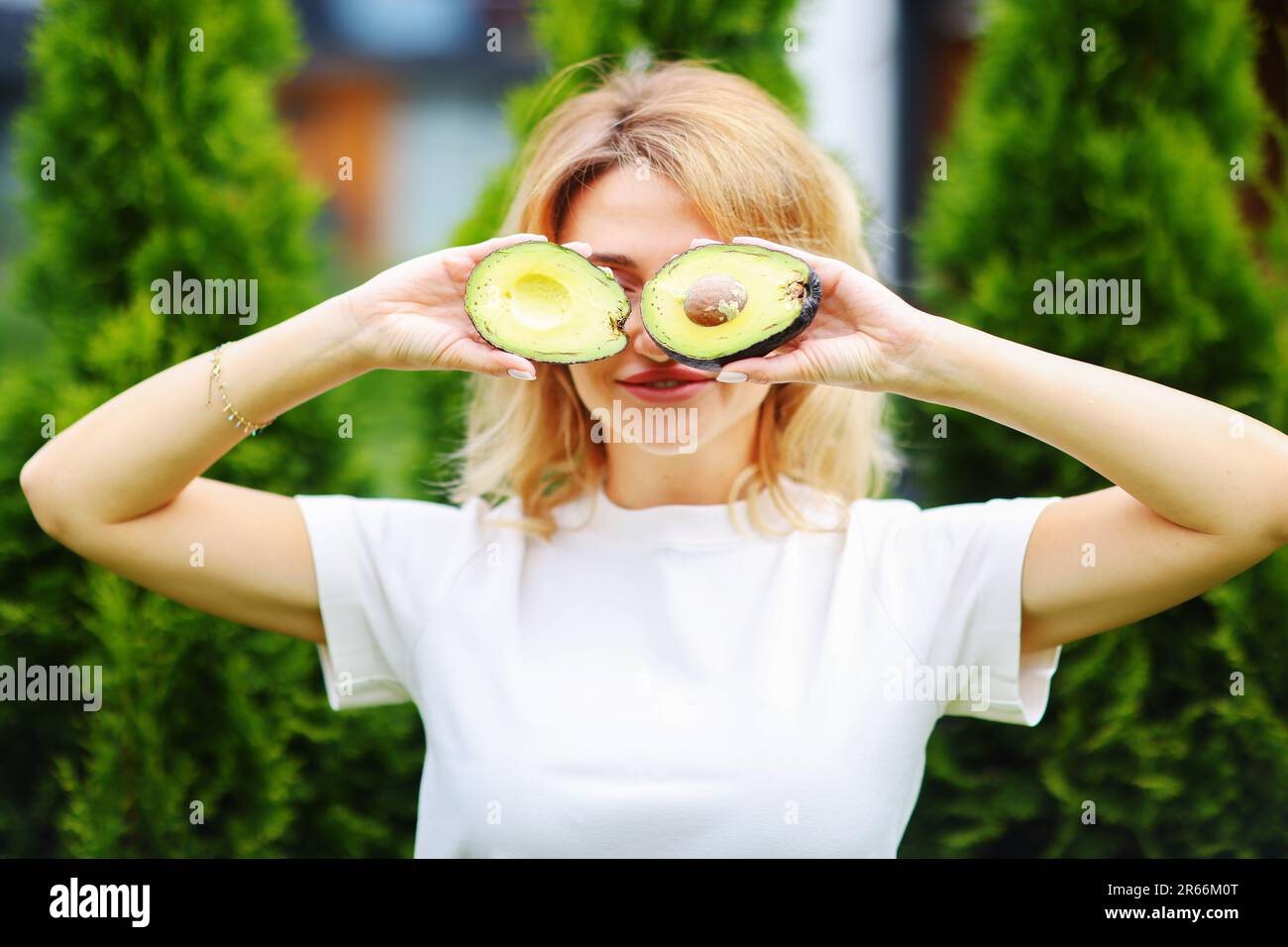 Happy young woman holding avocado halves to close eyes Stock Photo - Alamy