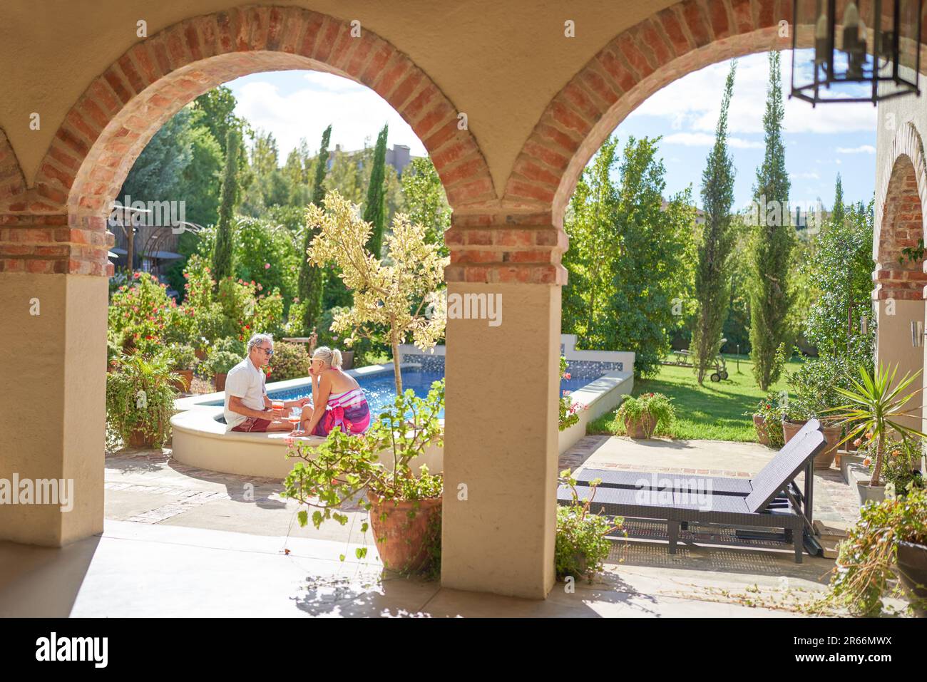 Senior couple talking and relaxing at sunny villa swimming pool Stock ...