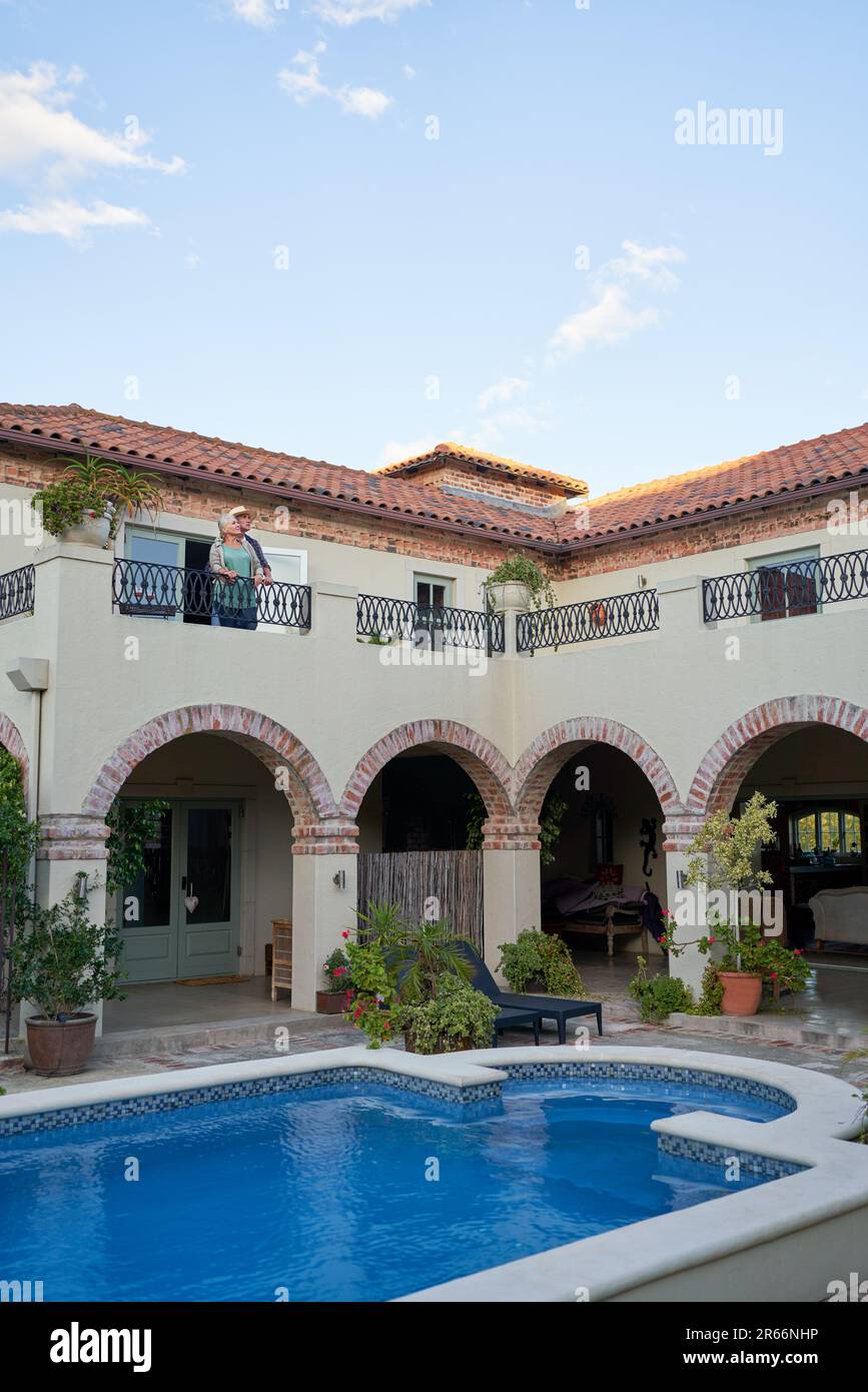 Senior couple at balcony railing above villa swimming pool Stock Photo ...
