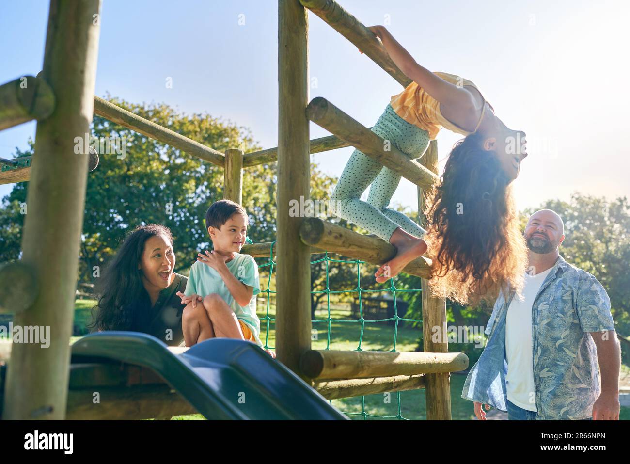 Happy family playing at playground equipment in sunny backyard Stock ...