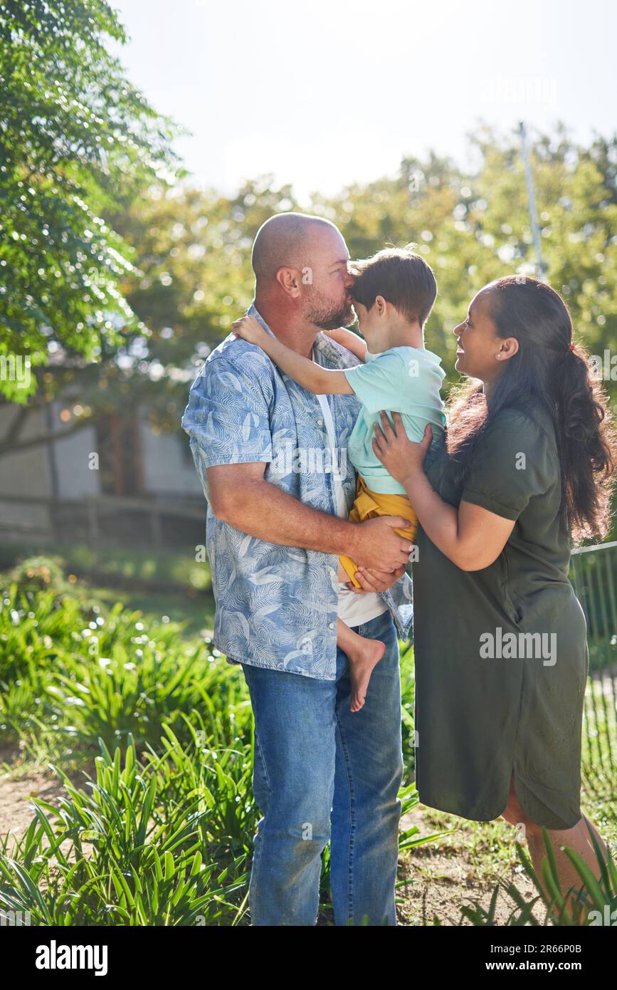 Parents holding son with Down Syndrome in sunny backyard Stock Photo ...