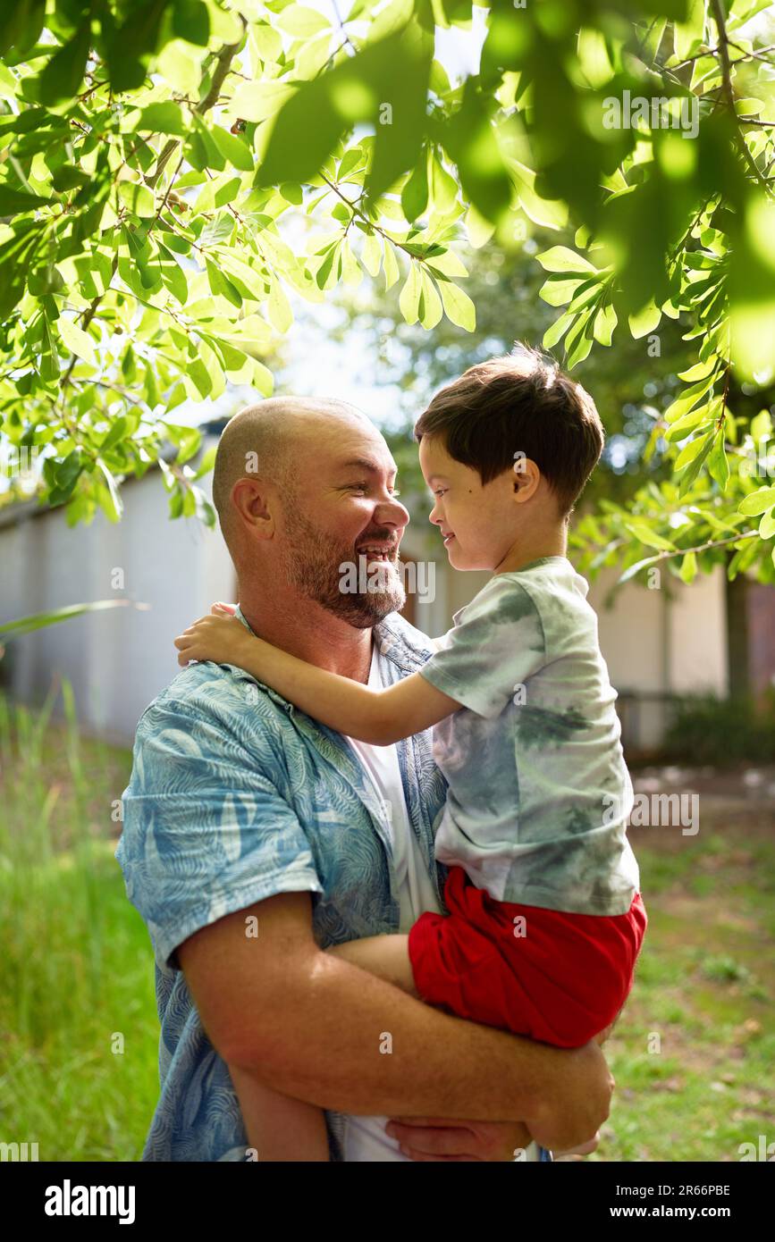 Happy father holding cute son with Down Syndrome in backyard Stock ...