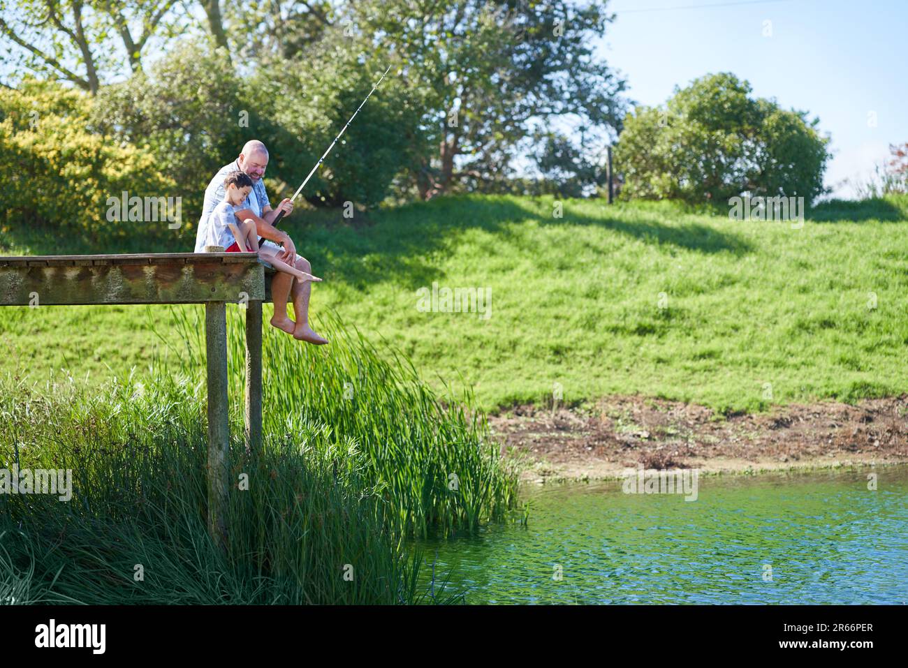 Father and son fishing on sunny summer lakeside dock Stock Photo - Alamy