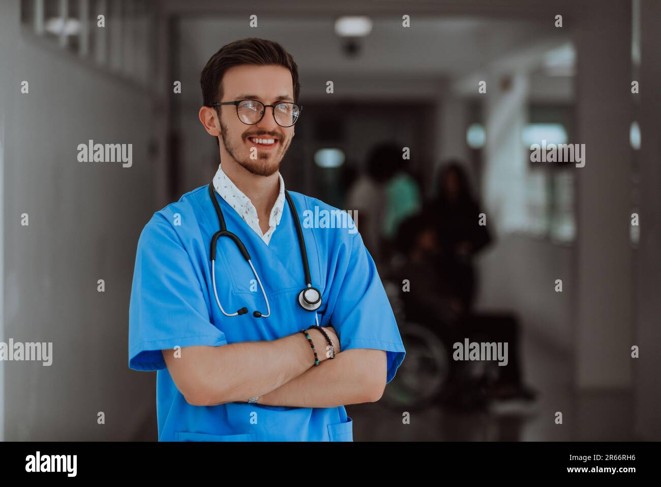 A determined young doctor with glasses stands confidently with crossed ...