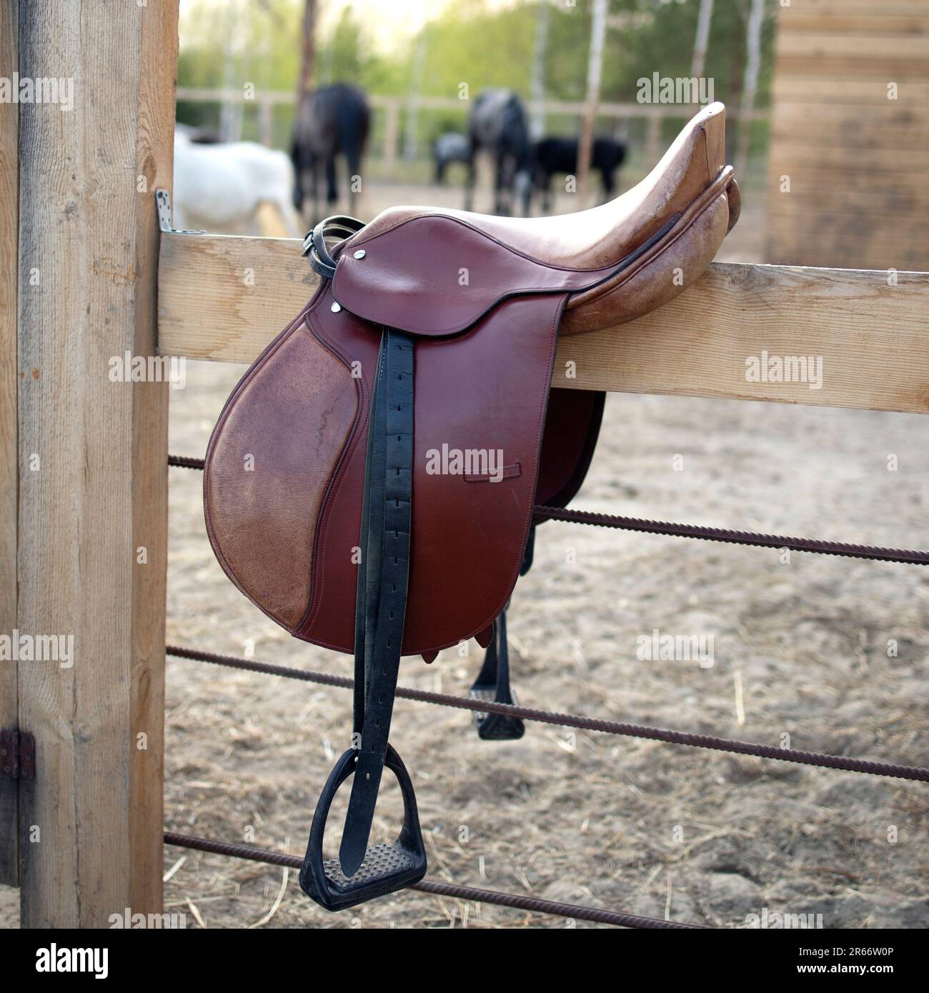 The horse's saddle lies on the fence in the stable before saddling the ...