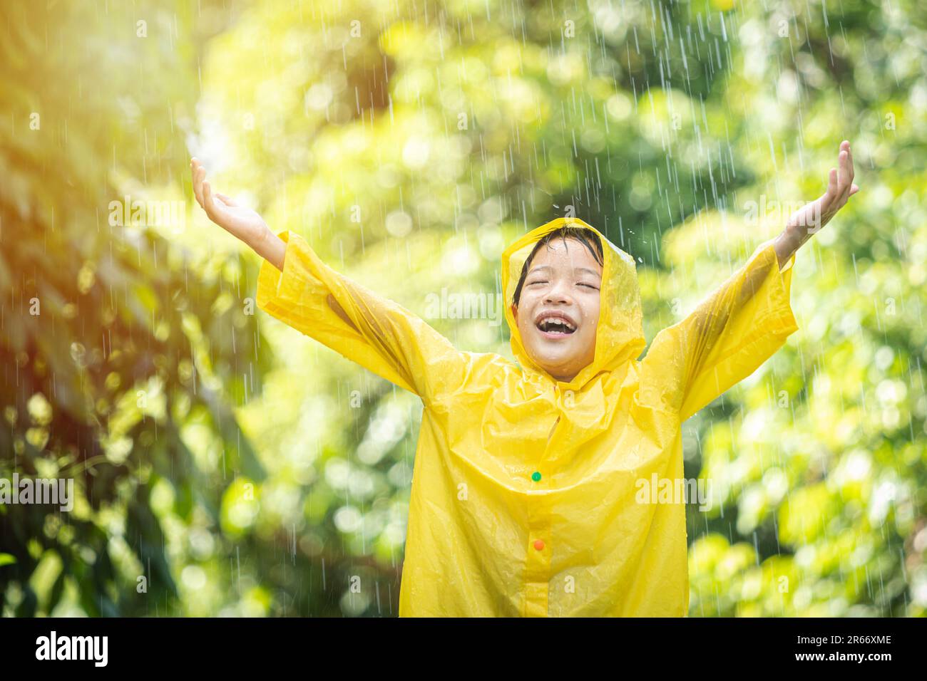 A boy wearing a yellow raincoat. Happy Asian little child having fun ...