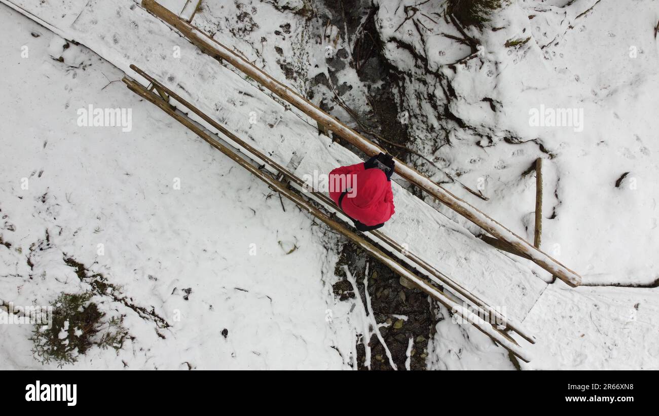 A man stands atop a rustic wooden bridge while operating a remote ...