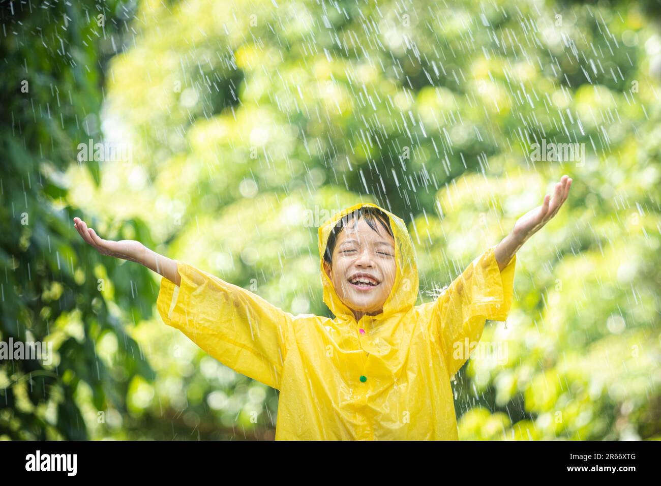 A boy wearing a yellow raincoat. Happy Asian little child having fun ...