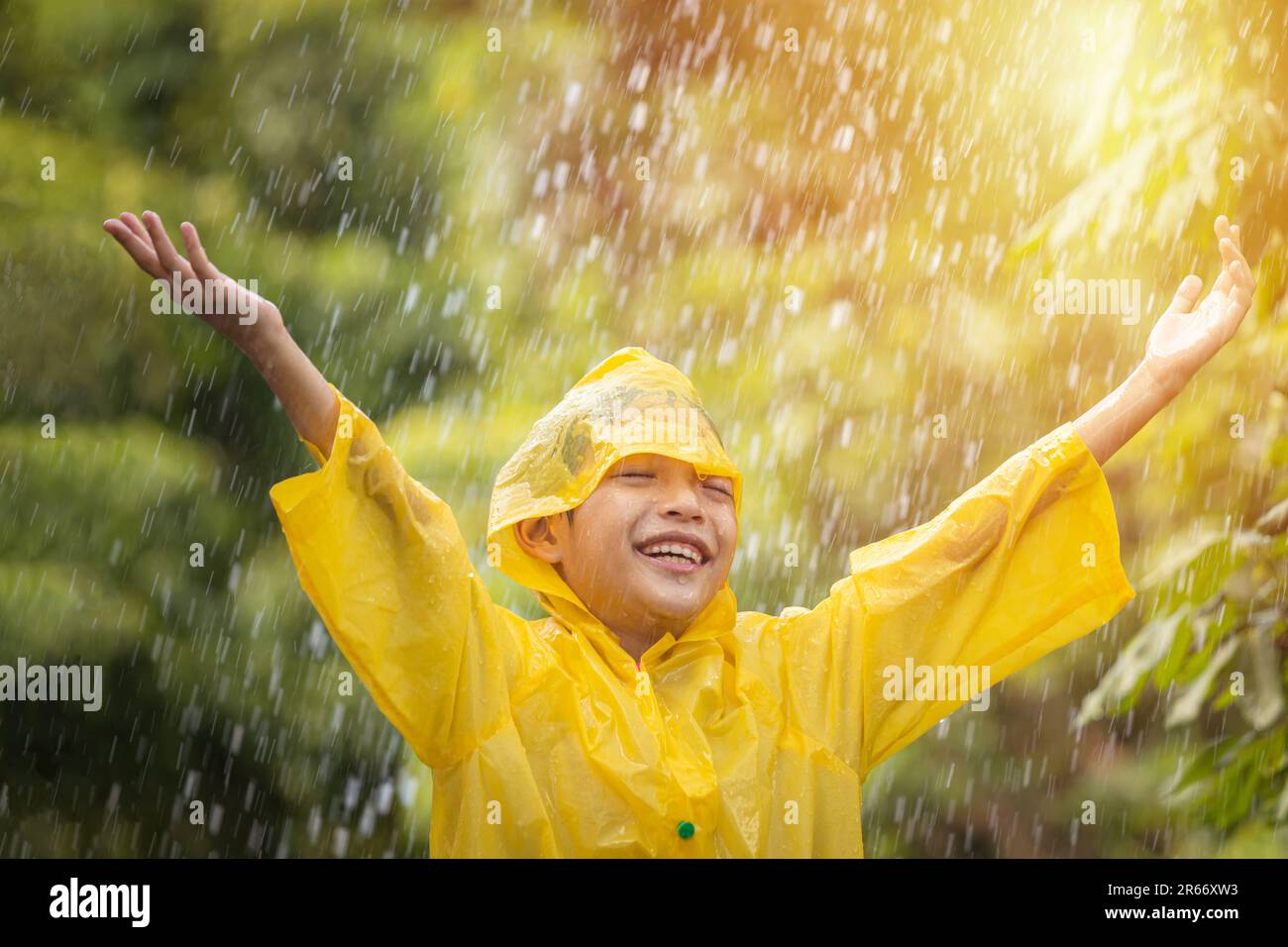 A boy wearing a yellow raincoat. Happy Asian little child having fun ...