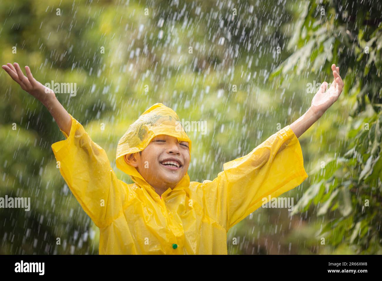 A boy wearing a yellow raincoat. Happy Asian little child having fun ...