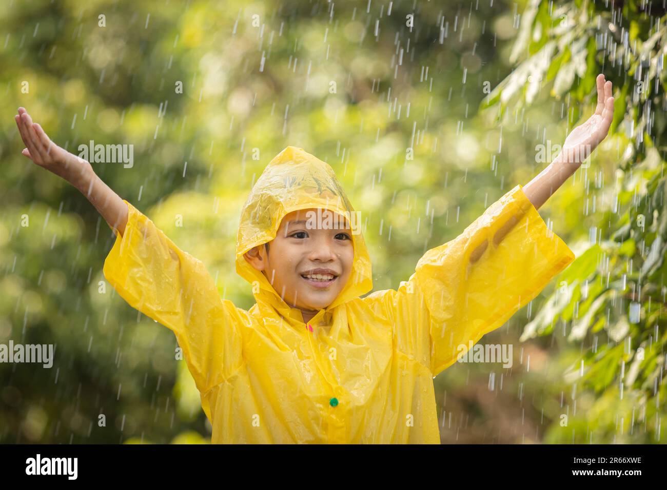 A boy wearing a yellow raincoat. Happy Asian little child having fun ...