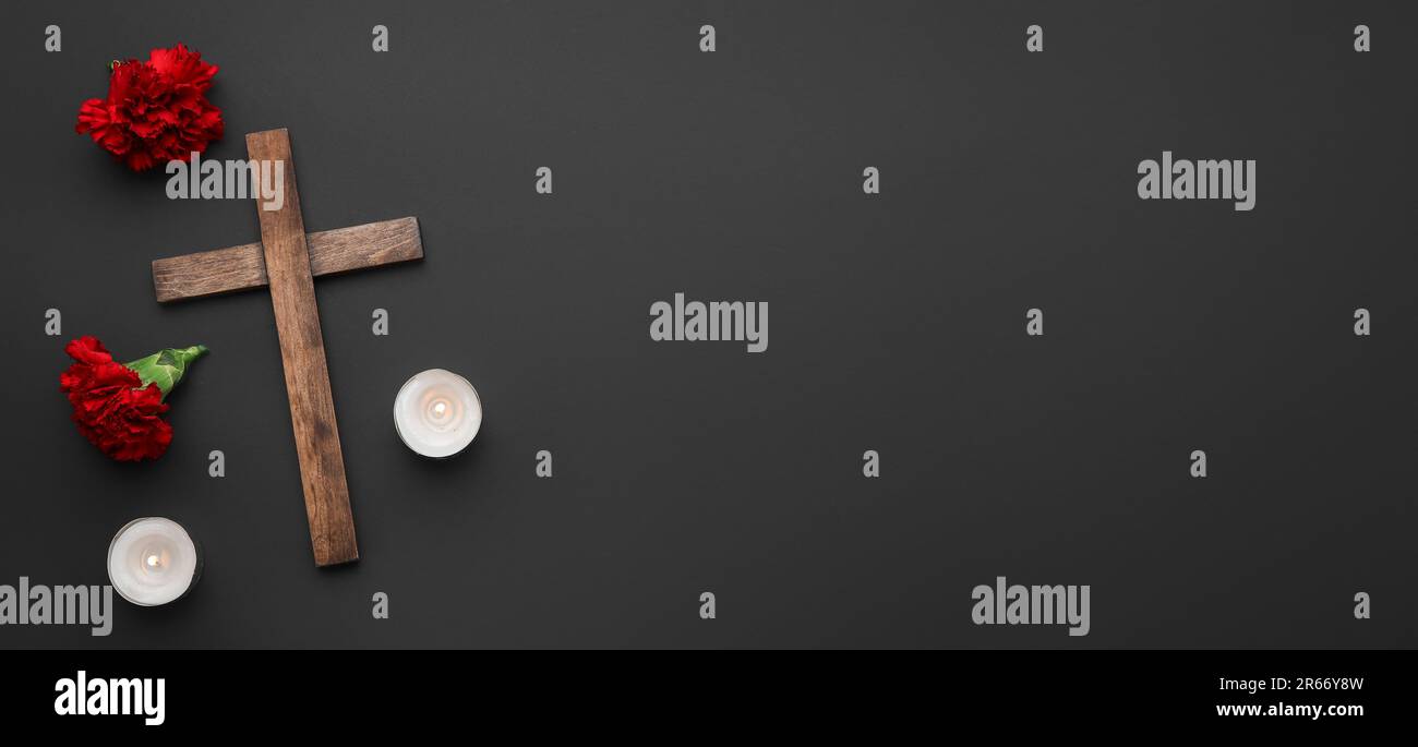 Wooden cross, carnation flowers and candles on dark background with ...