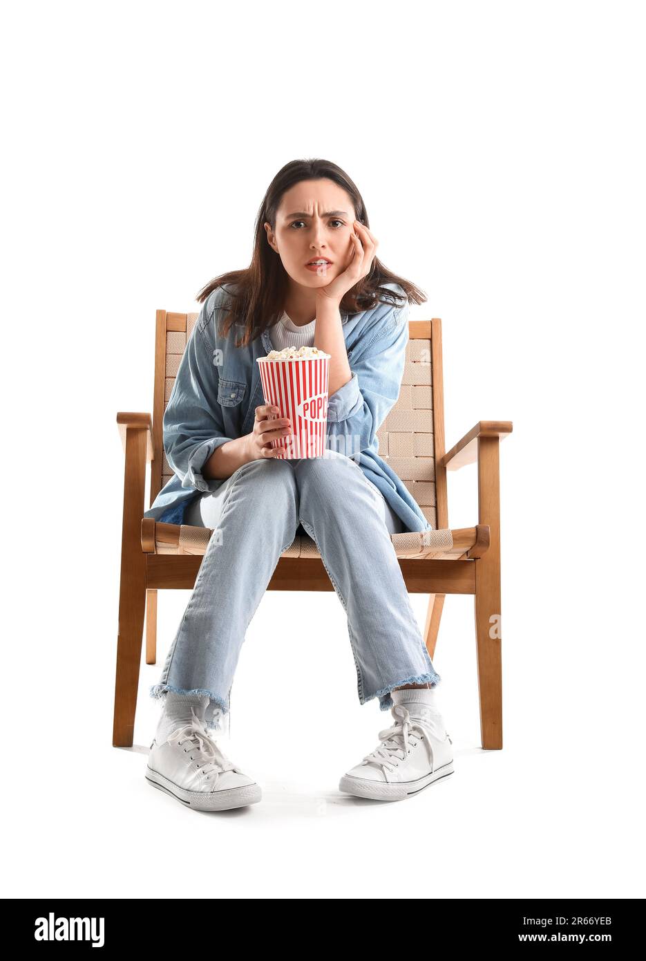 Upset young woman with popcorn sitting in armchair on white background ...