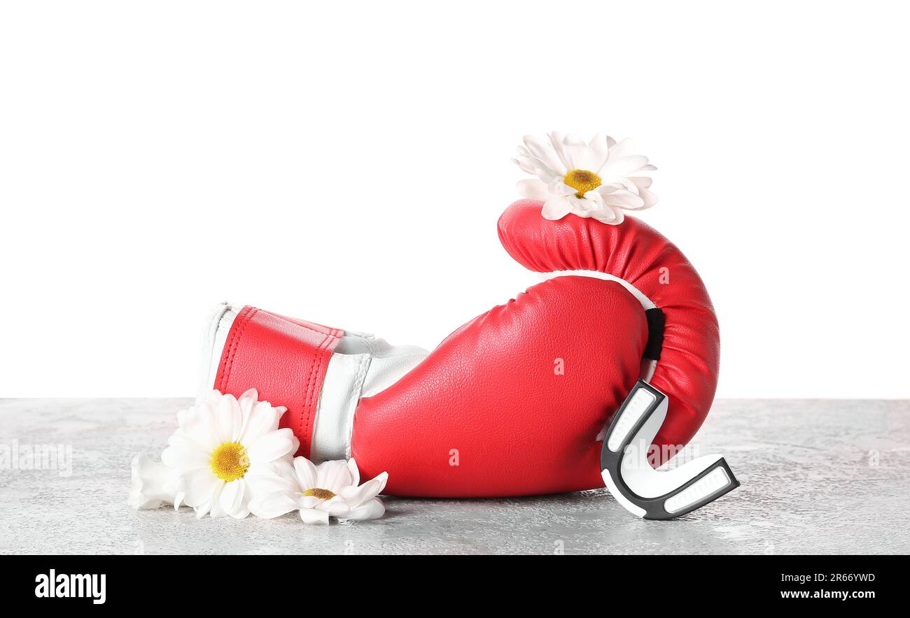 Boxing glove with daisy flowers and kappa on table against white ...