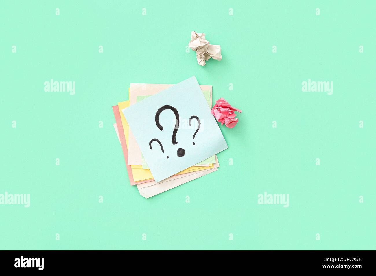 Sticky notes with question marks and crumpled paper on green background ...