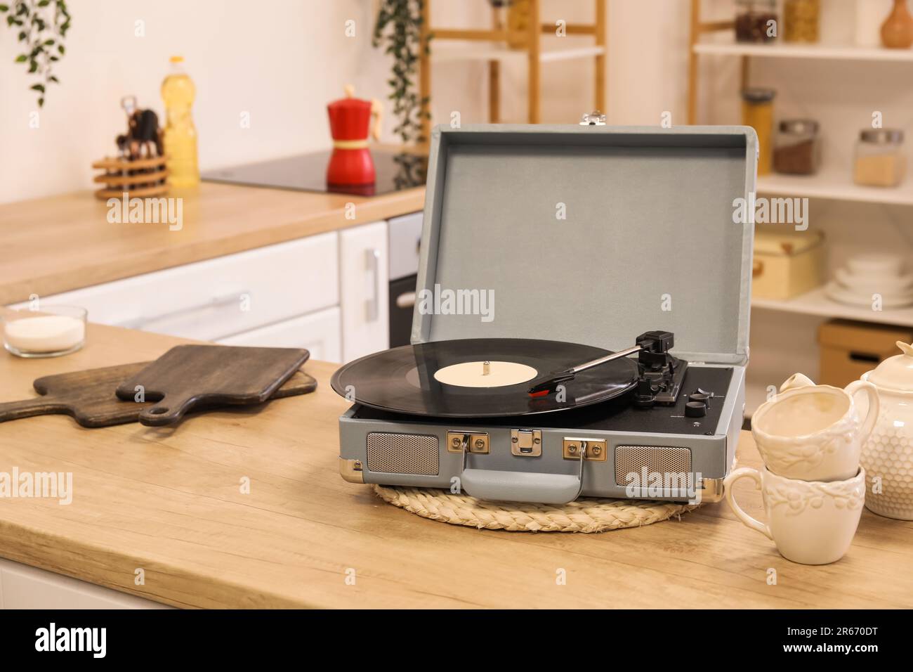 Record player with vinyl disk, cups and teapot on counter in kitchen ...