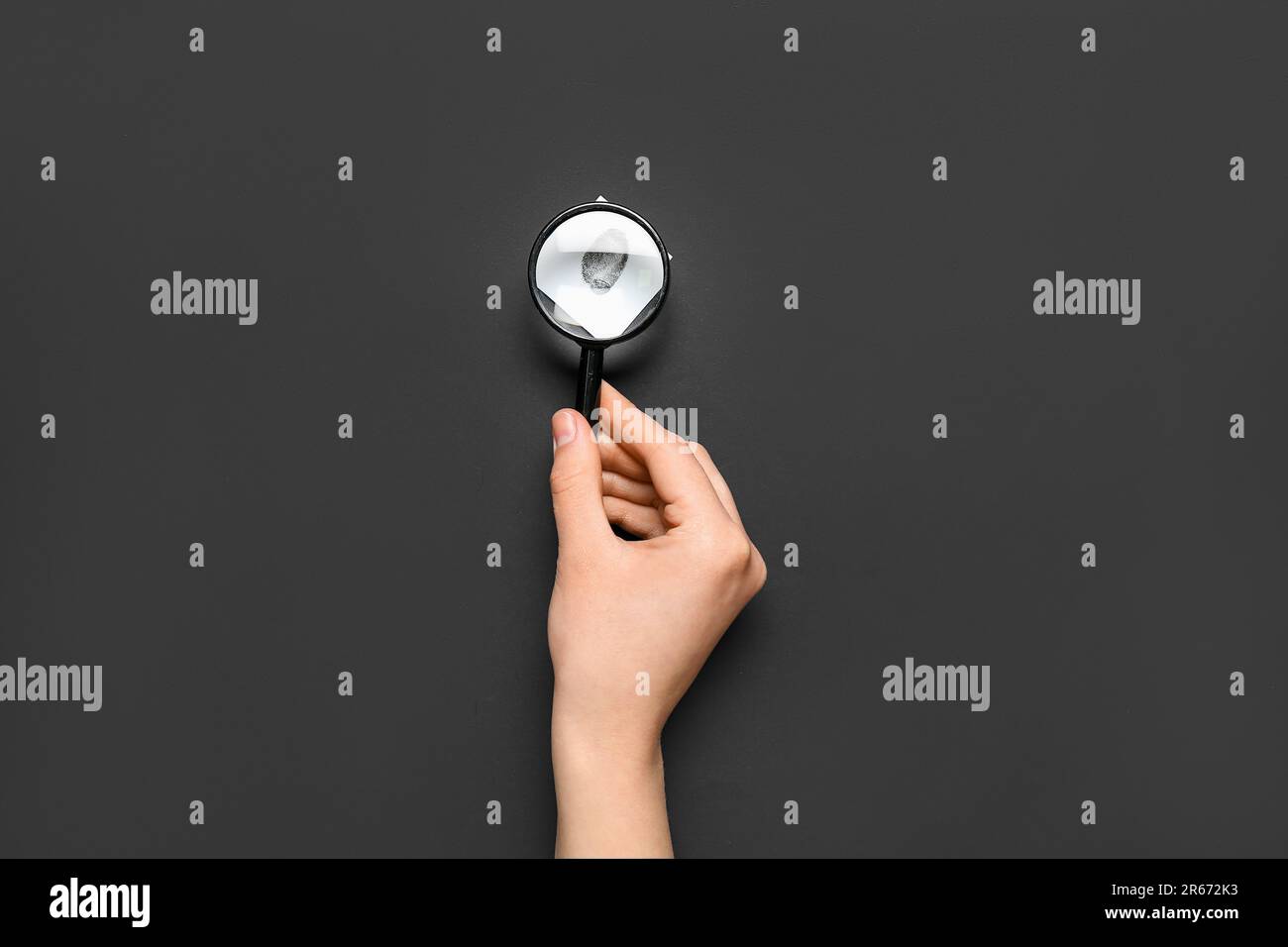 Female hand with magnifier and paper with fingerprint on black ...