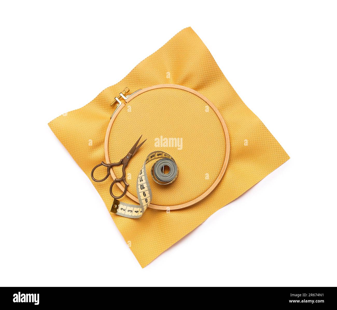 Embroidery hoop with orange canvas, scissors and measuring tape ...