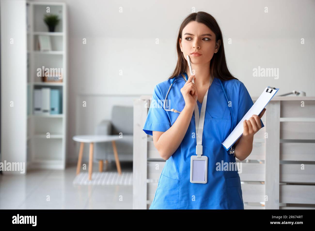 Thoughtful female medical intern with clipboard at hospital Stock Photo ...