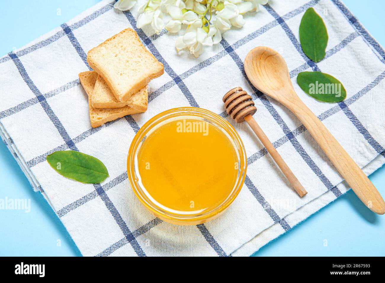 Bowl of honey with flowers of acacia and crackers on blue background ...