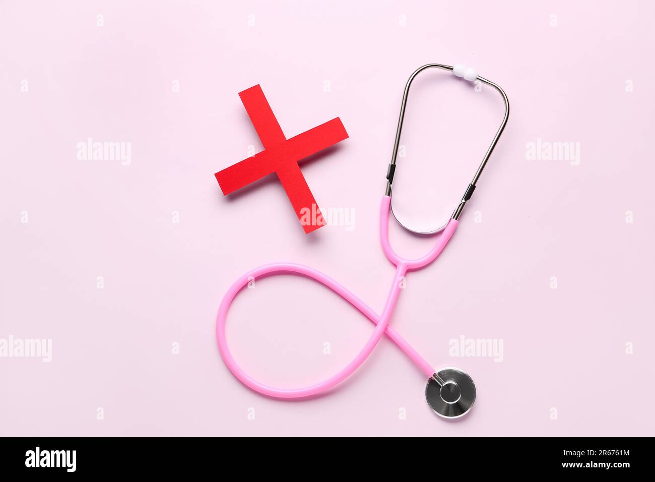 Stethoscope and red cross on pink background Stock Photo - Alamy