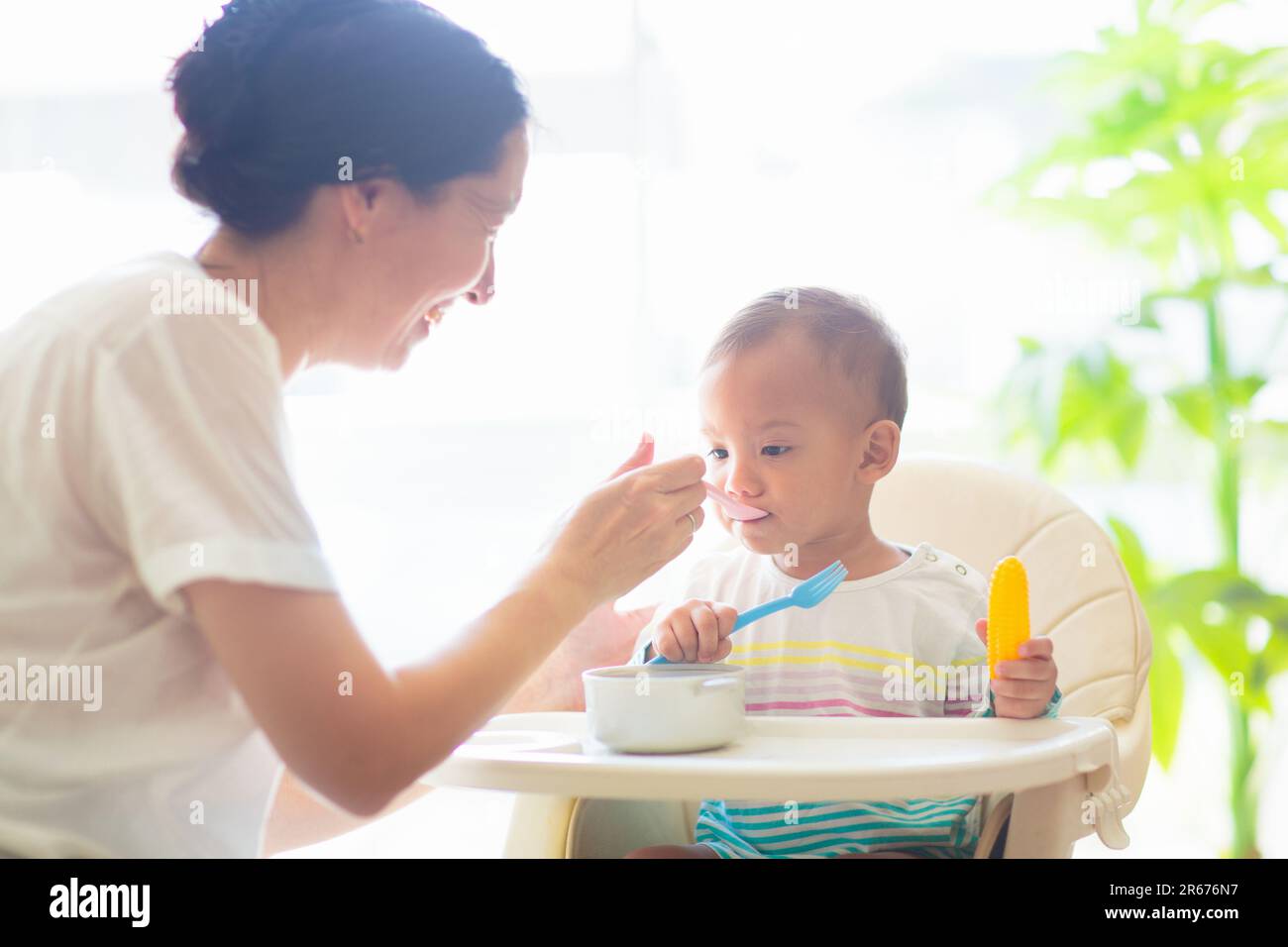 Baby eating in high chair. Asian baby boy with drink and lunch. Infant ...